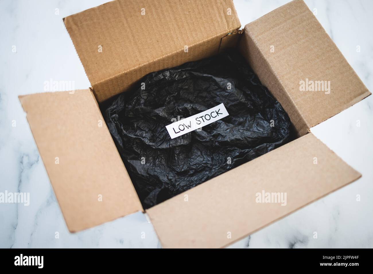 Low stock text inside of empty delivery parcel with black padding on ...