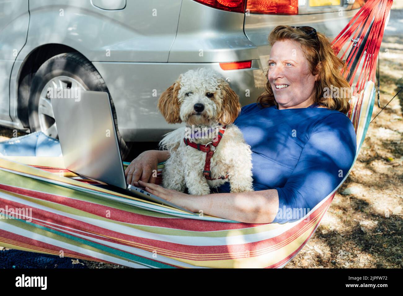 Adult woman working on laptop pc while lying in hammock, with her ...