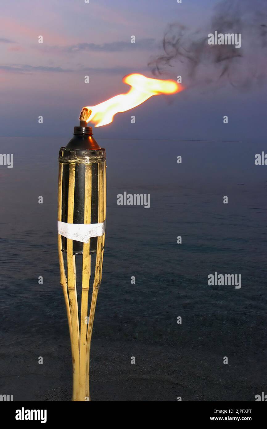 Torch inserted into the sand at a beach near the sea Stock Photo - Alamy