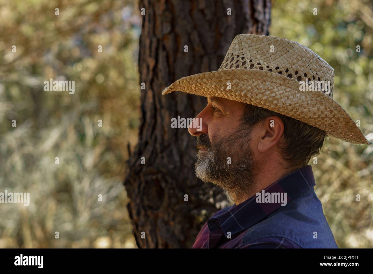 close-up of a man with beard and hat in profile in the forest with a ...