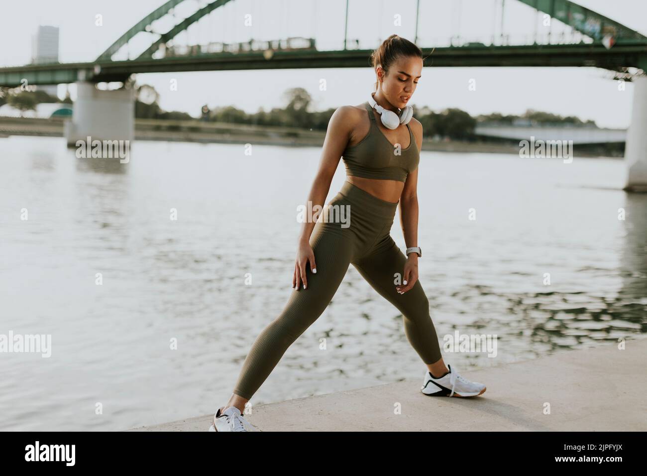 Pretty young woman in sportswear stretching on a river promenade Stock ...
