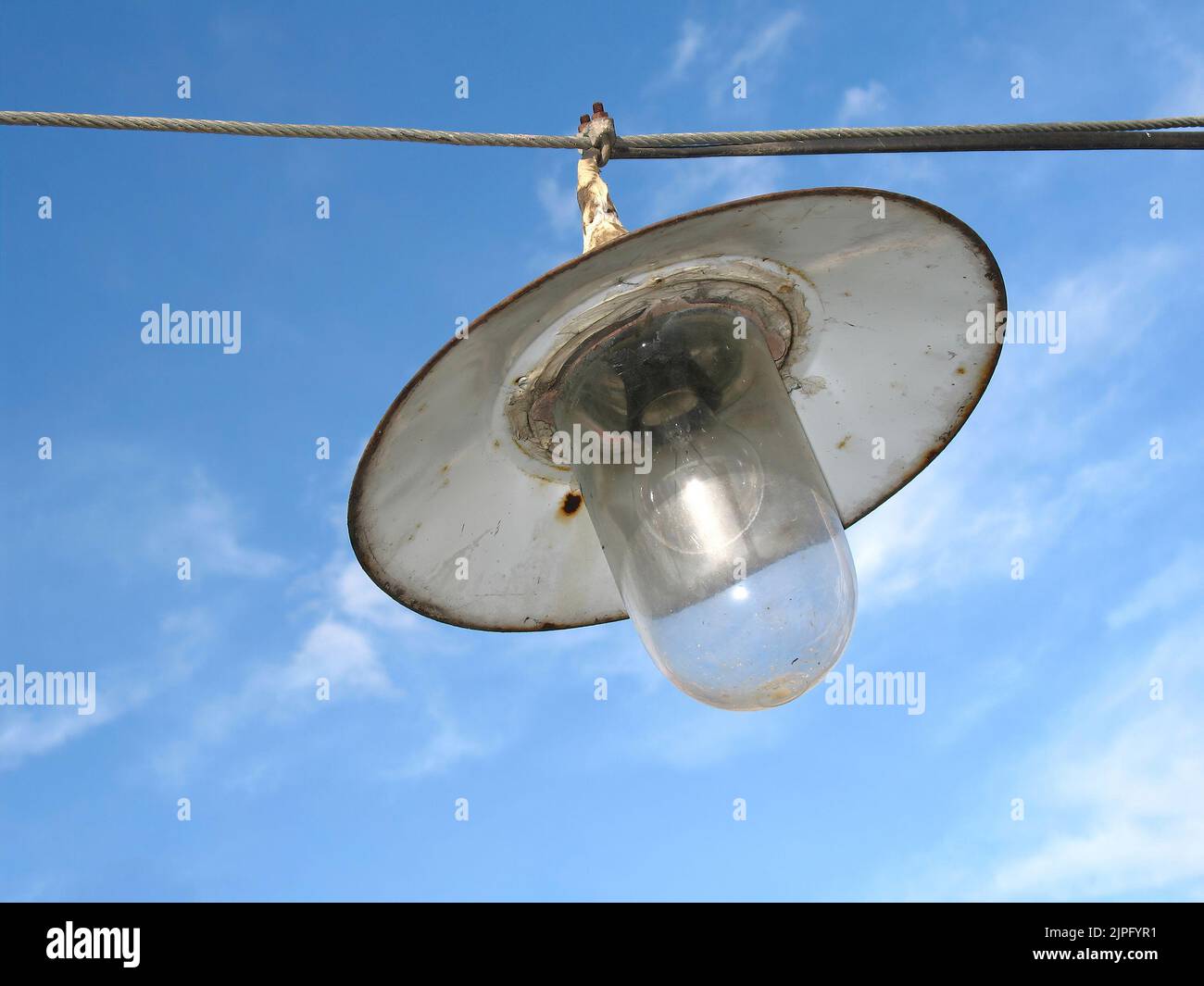 An old vintage lantern hanging on a wire with light bulb - sky ...
