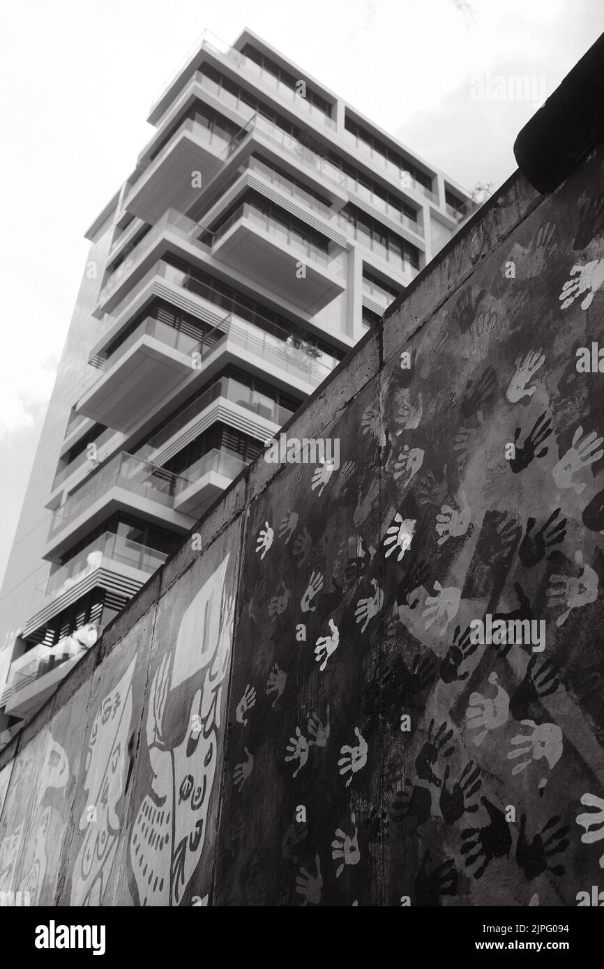 A vertical shot of a modern high-rise building behind a concrete wall ...