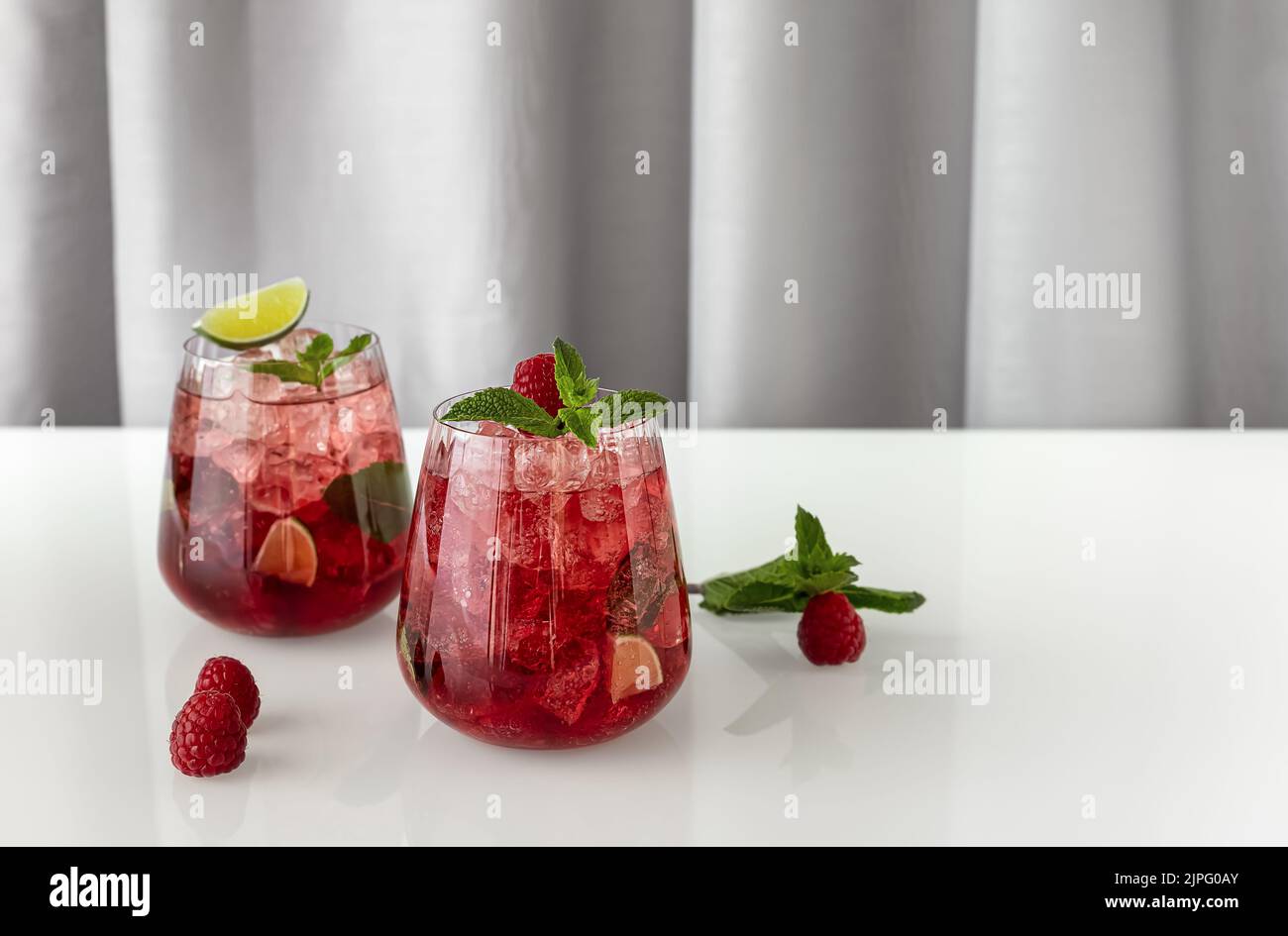 Fresh summer lemonade with raspberry, lime, soda water, and ice in ...