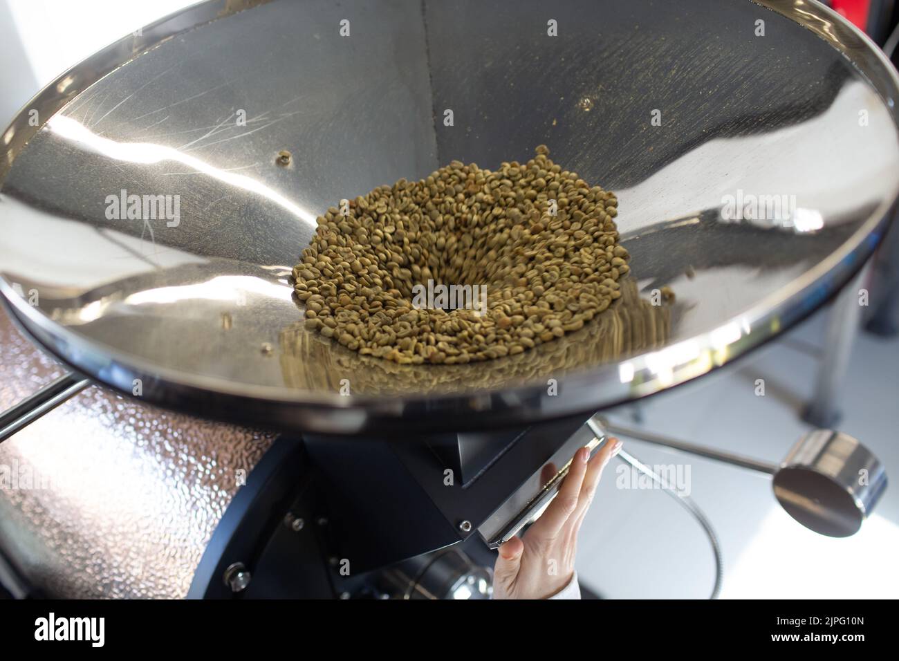 Coffee roaster machine at coffee roasting process. Young woman worker ...