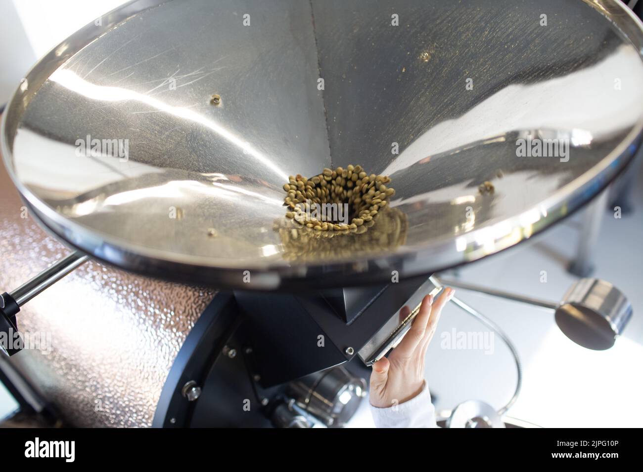 Coffee roaster machine at coffee roasting process. Young woman worker ...