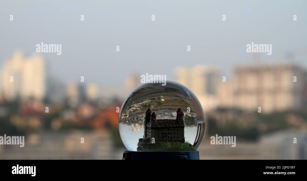 Miniature castle in toy glass globe with real cityscape soft focus ...