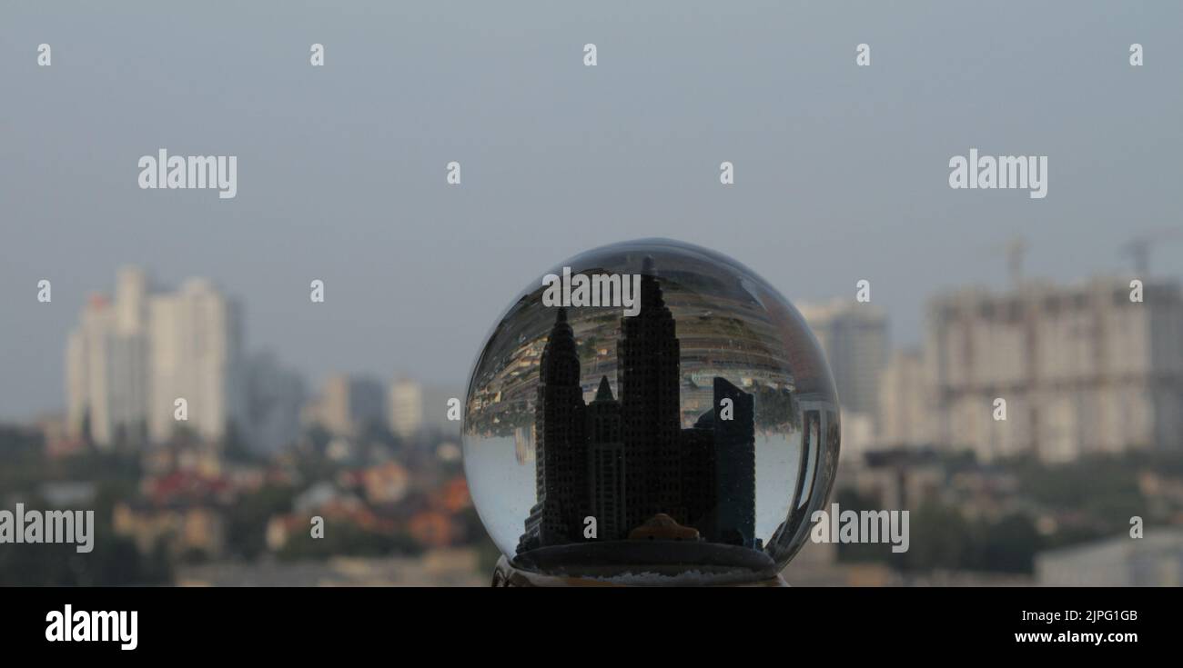 Toy buildings inside a souvenir crystal ball with reflection of a real ...