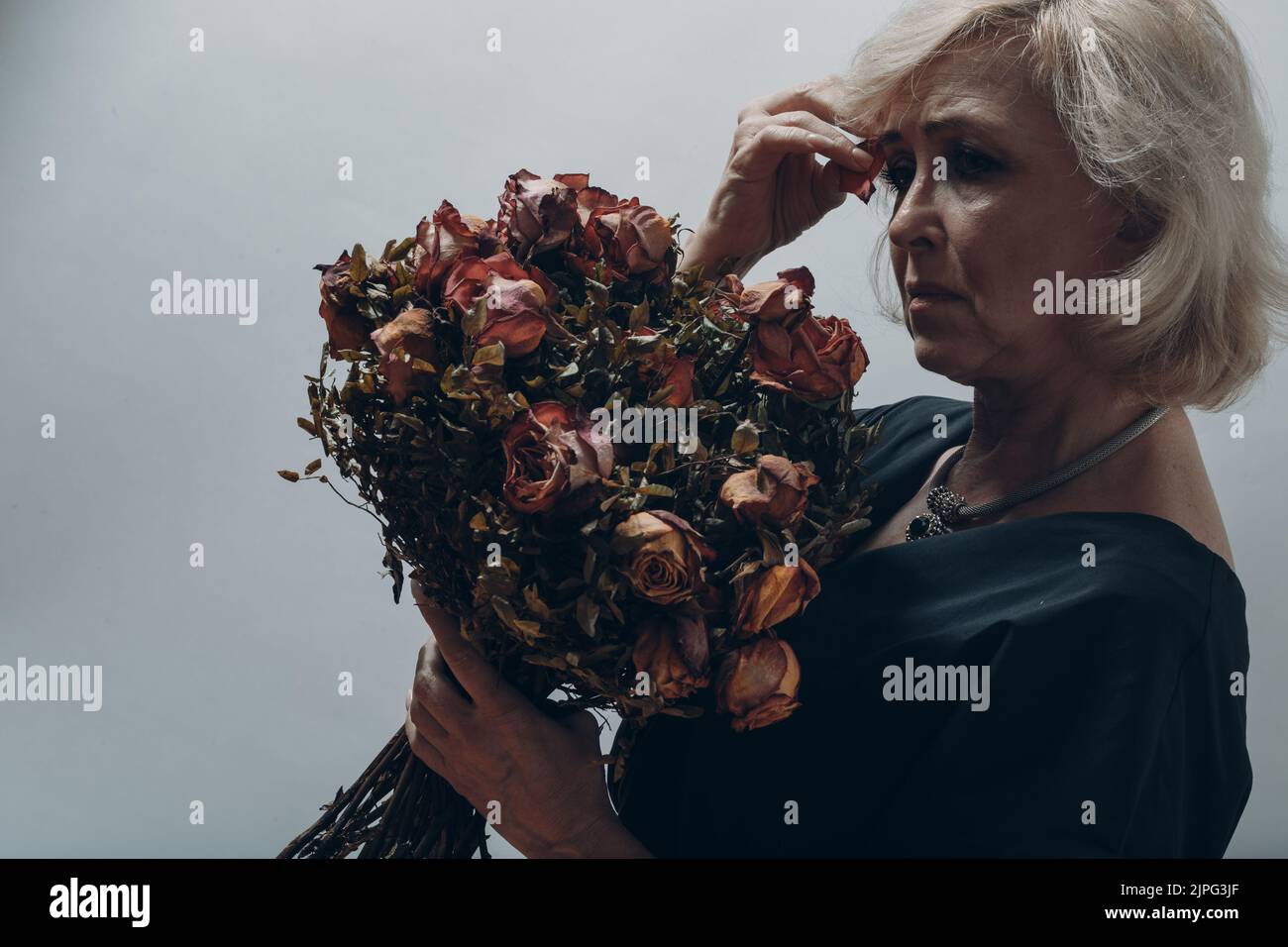 Upset elderly woman hold withered dry old rose flowers bouquet Stock ...