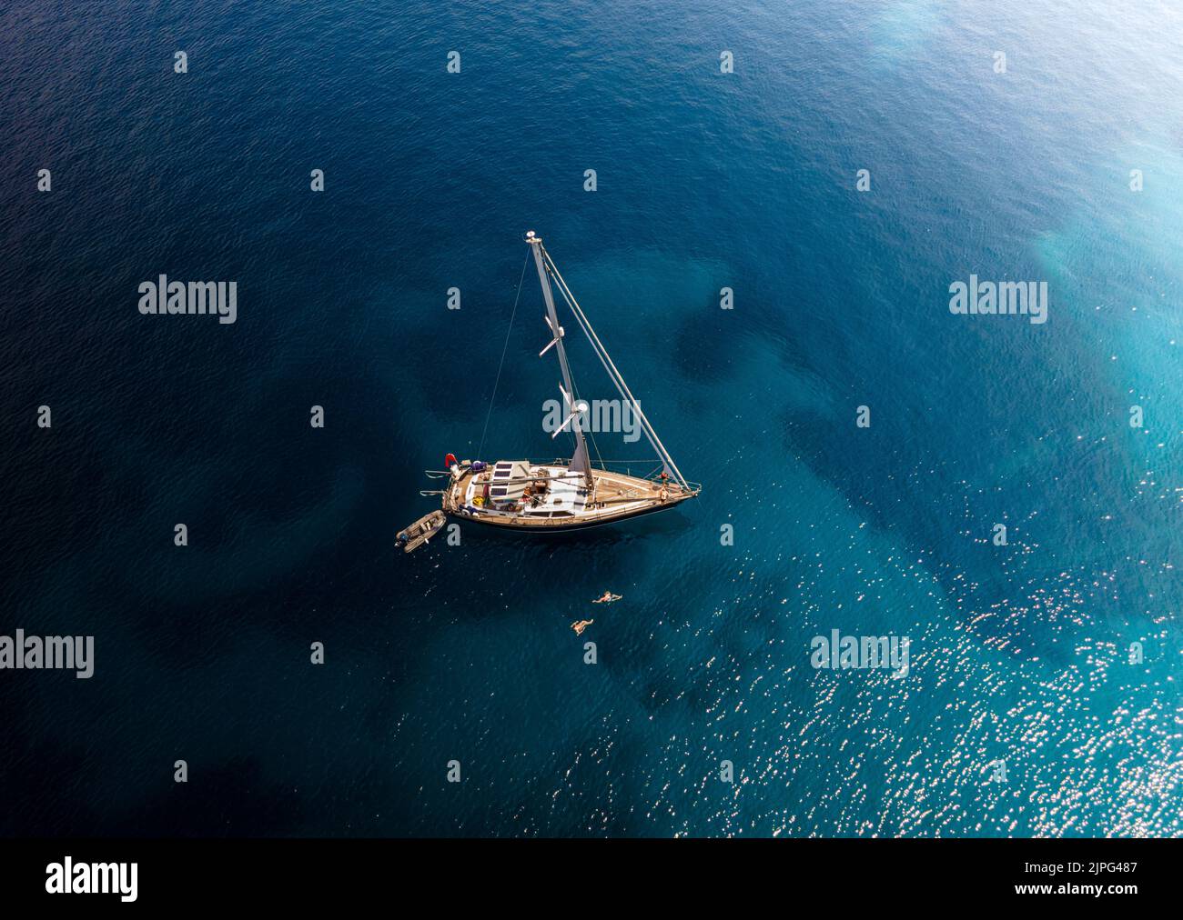 The vertical aerial view of an empty wooden boat on the blue water ...