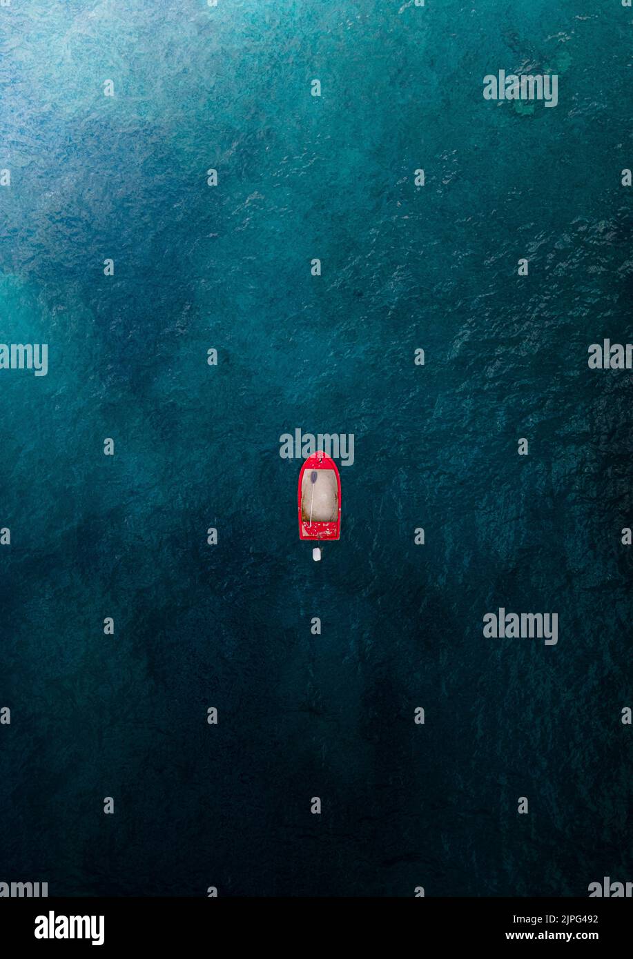 The vertical aerial view of an empty red boat on the blue water Stock ...