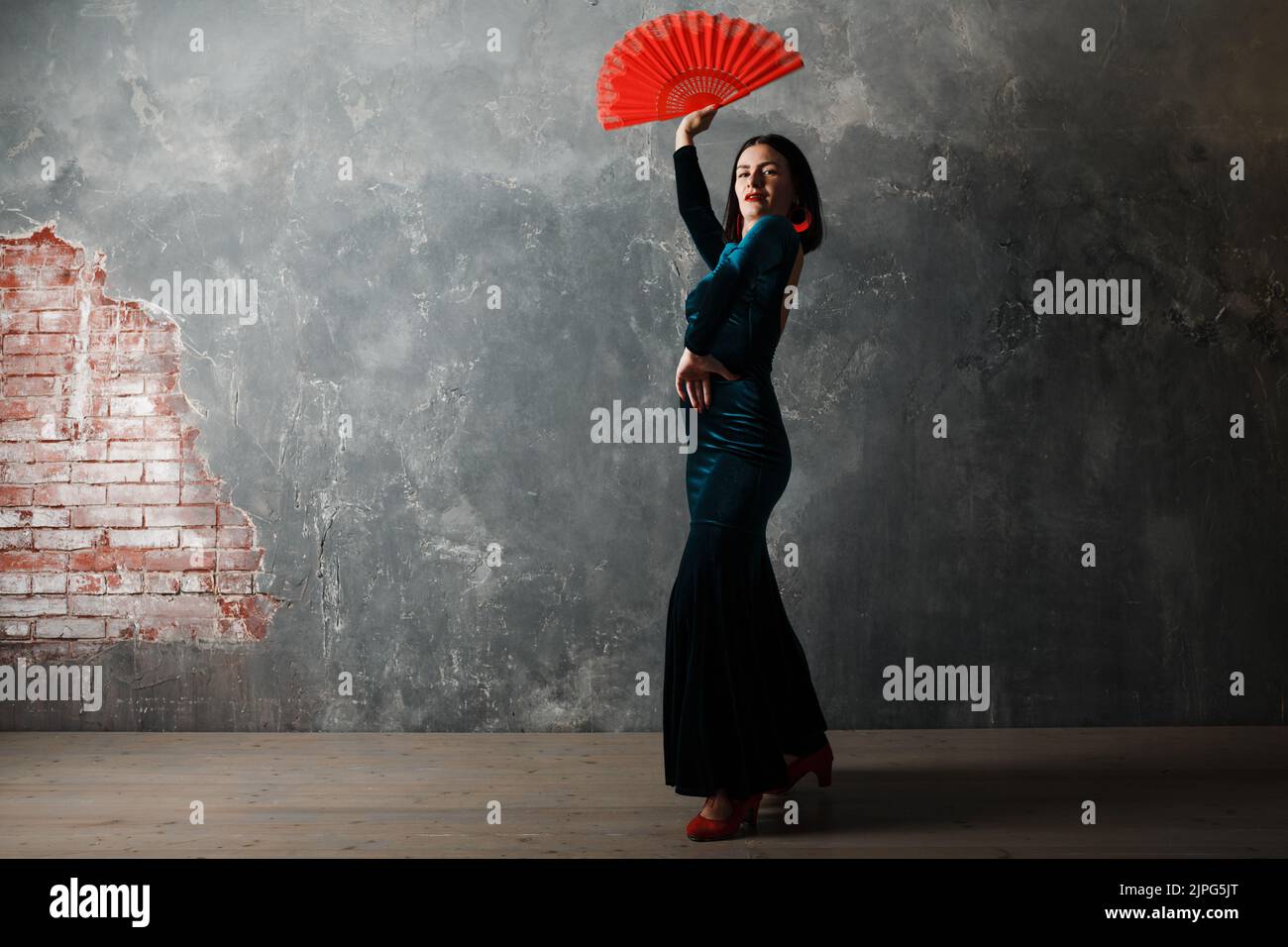 Young adult spanish woman dancing flamenco on gray vintage studio ...