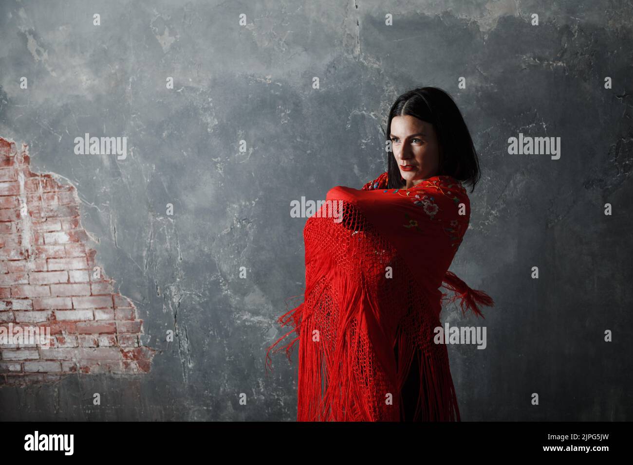 Young adult spanish woman dancing flamenco on gray vintage studio ...
