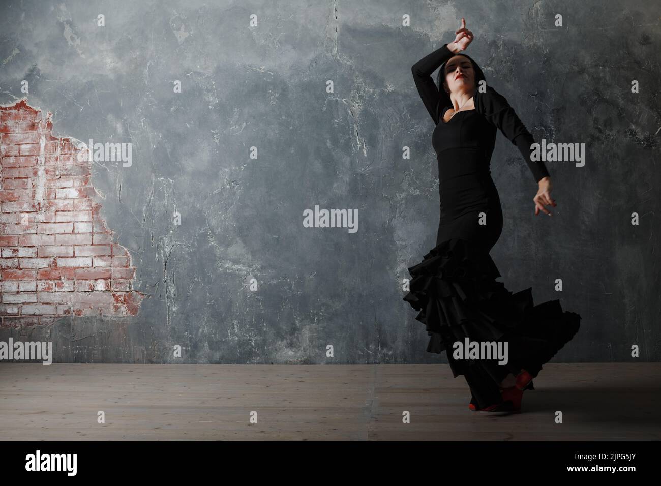 Young adult spanish woman dancing flamenco on gray vintage studio ...
