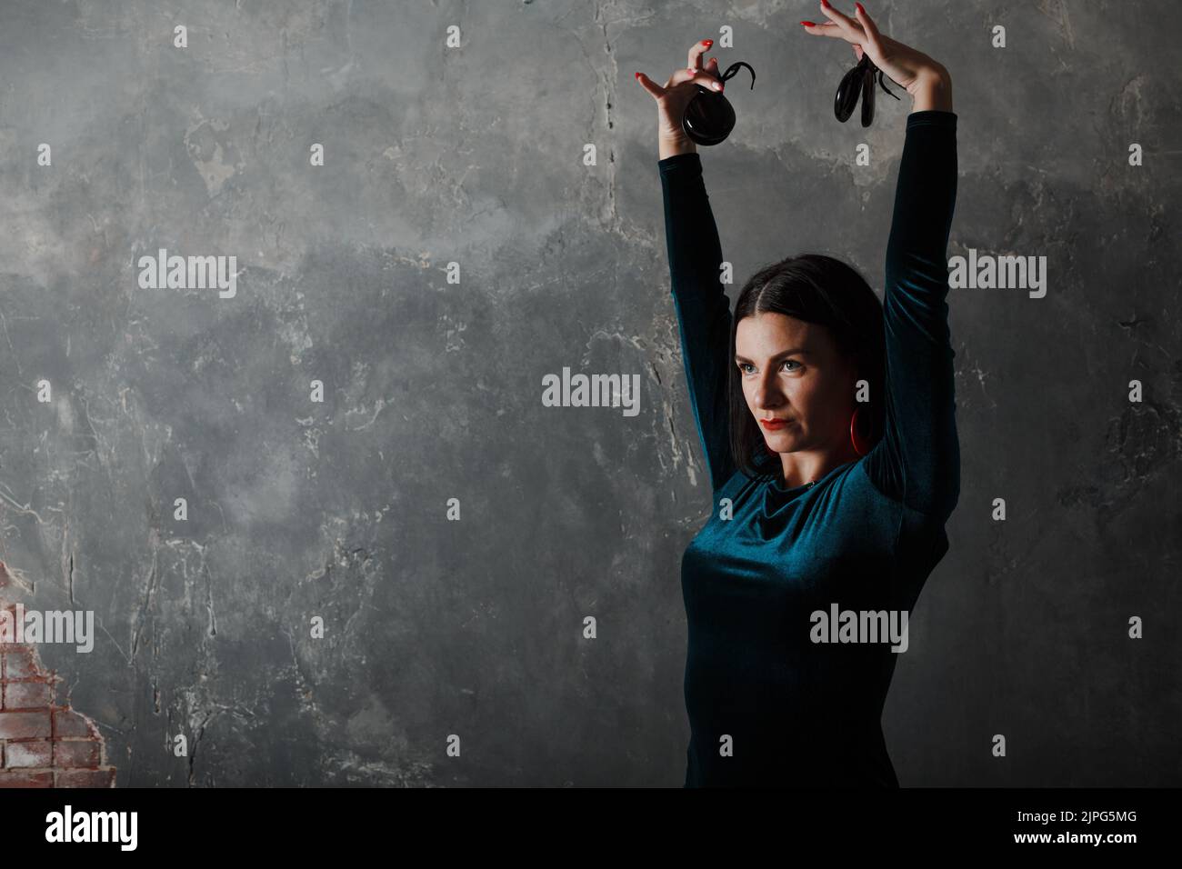 Young adult spanish woman dancing flamenco on grey vintage studio ...