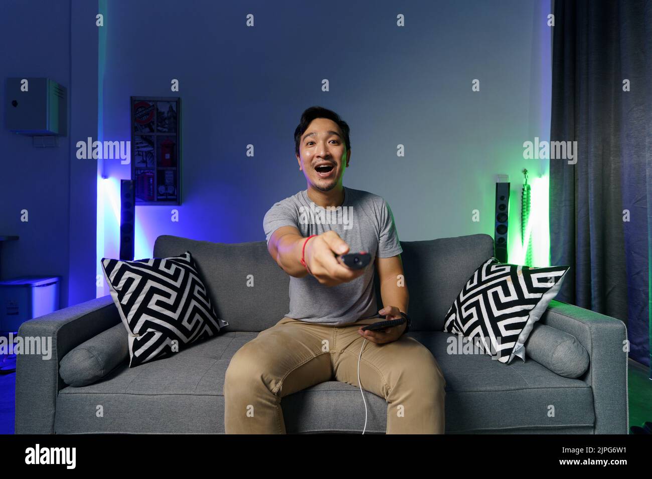 A young Southeast Asian male chilling and watching TV in the living ...