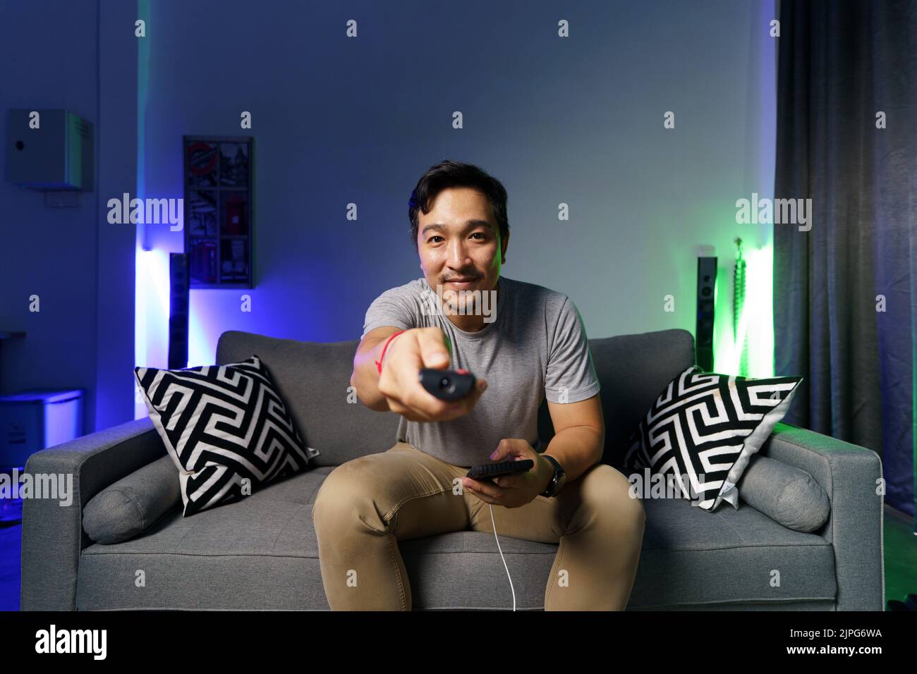 A young Southeast Asian male chilling and watching TV in the living ...