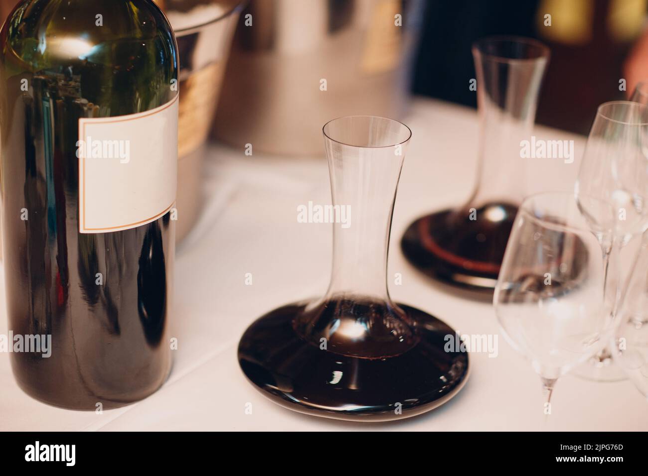 the waiter pours elite red wine into the decanter on the table in the ...