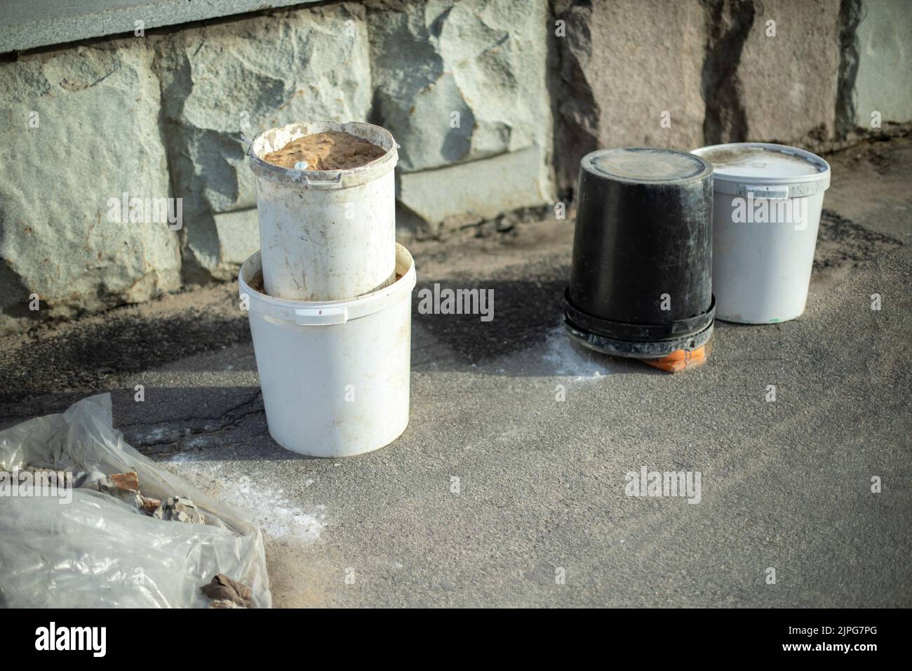 Buckets of sand against wall. Building material for repair. Buckets of ...