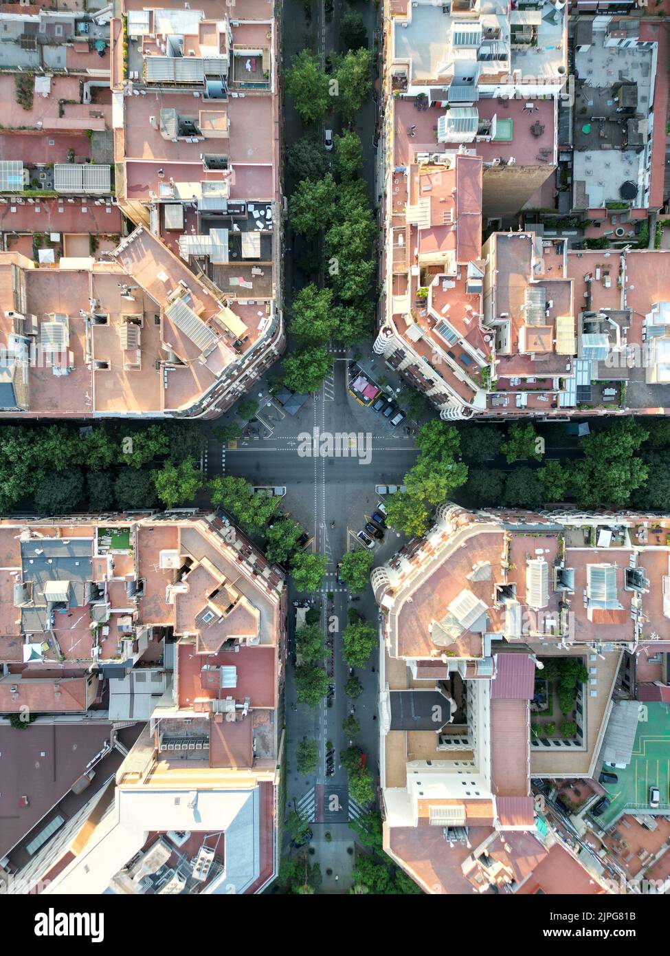 The vertical top view of a crossroad with trees and colorful rooftops ...