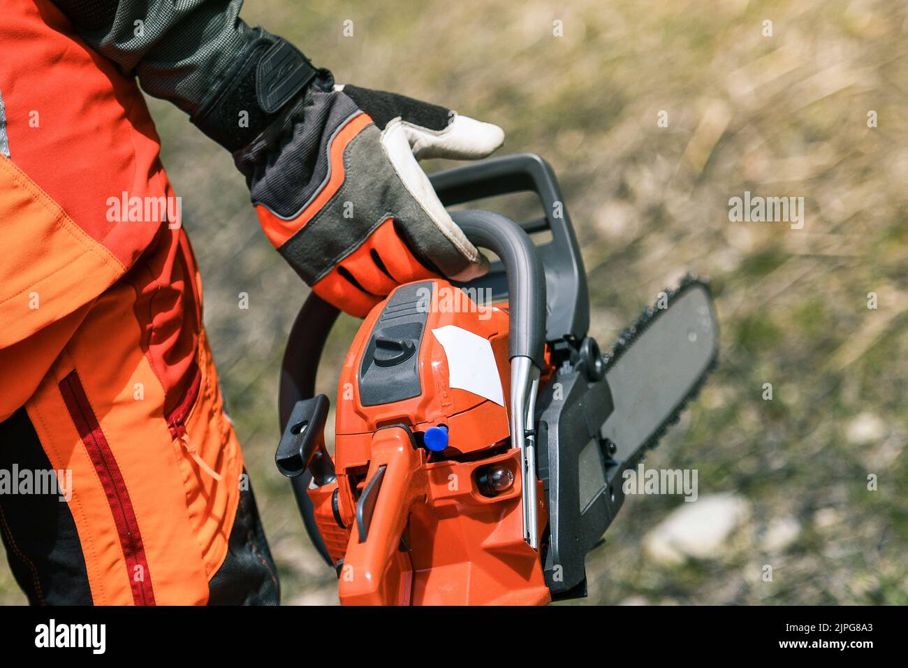 Close up view of an hand holding a chainsaw. Lumberjack at work wears ...