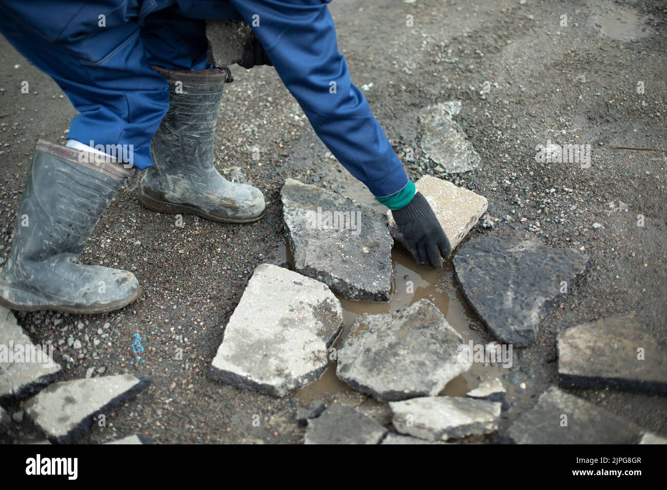 Repair of road. Broken stones. Construction details. Worker cleans up ...
