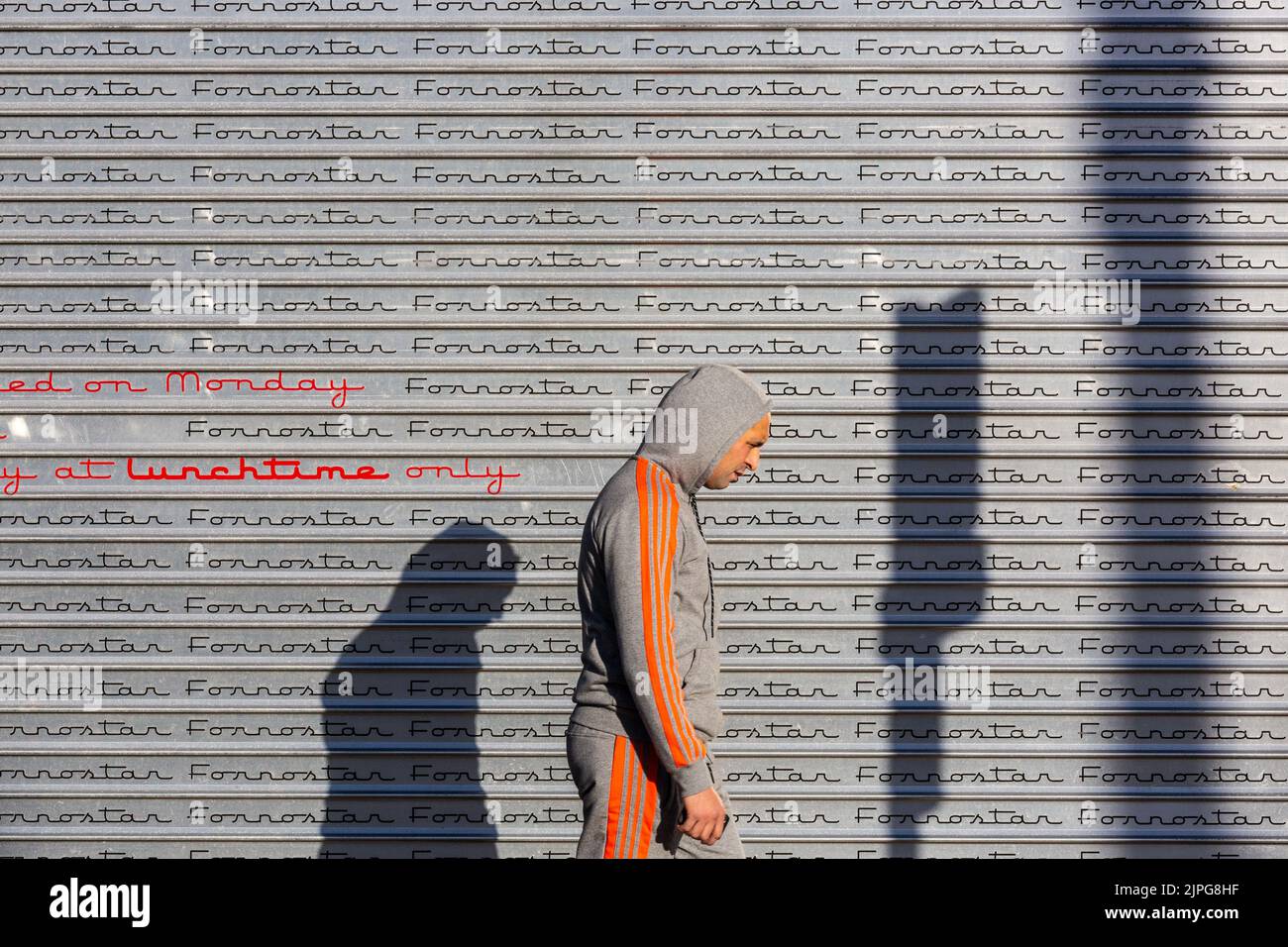 Man walking past a gray shutter Stock Photo - Alamy