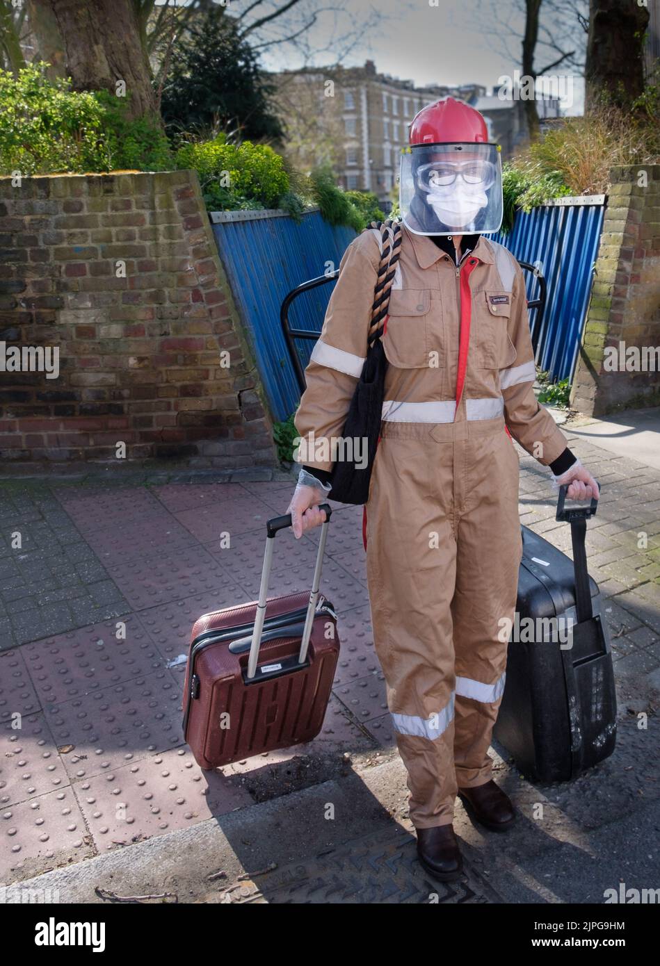 Woman in mask, helmet, and firefighters clothing pulling suitcases in ...