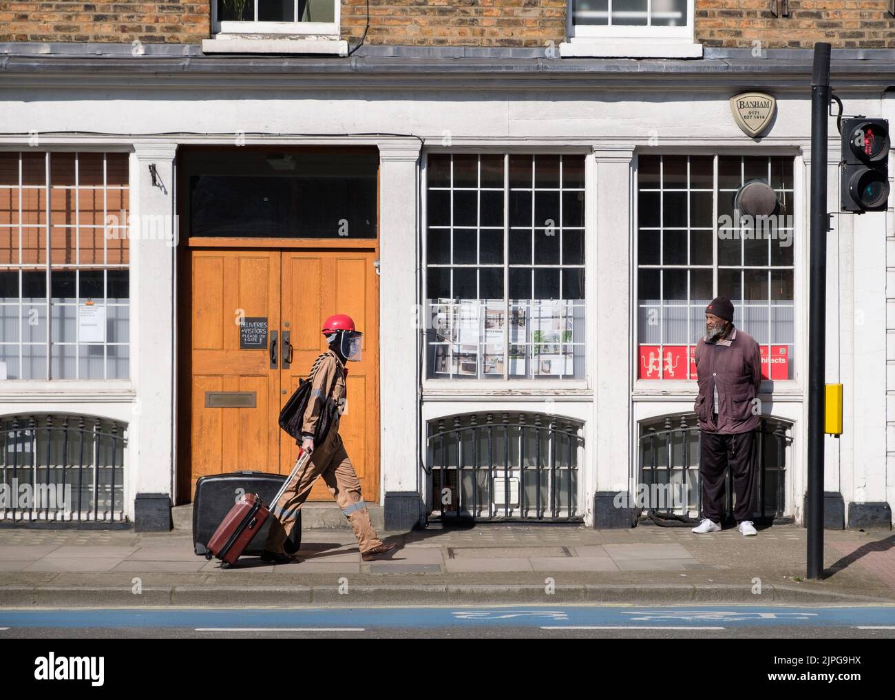 Woman in mask, helmet, and firefighters clothing pulling suitcases in ...