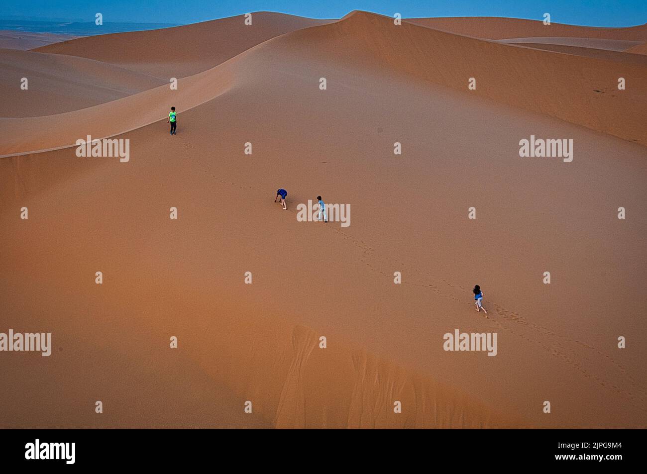 Children climb a sand dune in Merzouga, Sahara desert, Morocco Stock ...