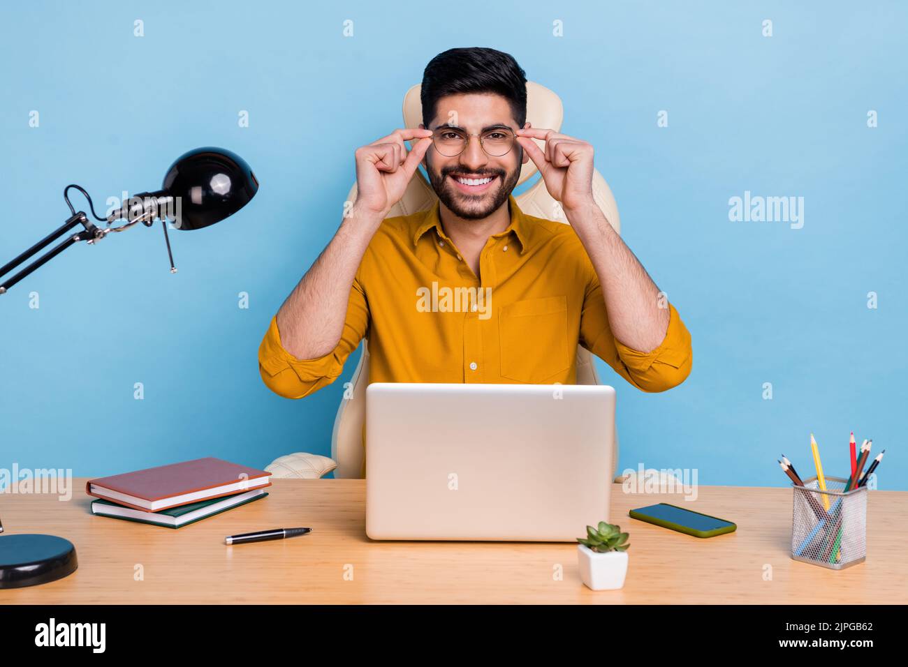 Portrait of cheerful clever agent man sit chair arms touch glasses use ...