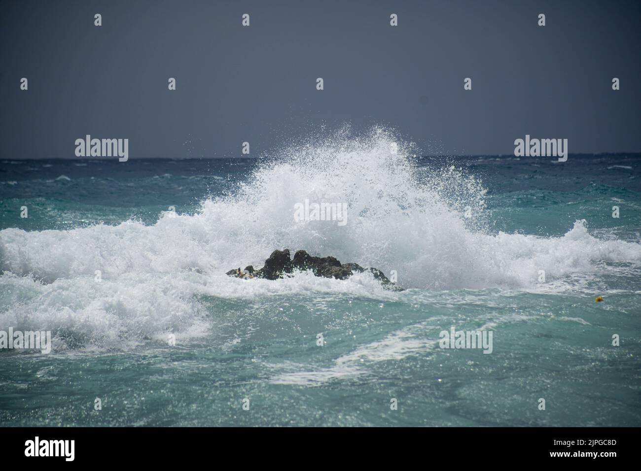 In the picture you can see a beautiful wave hitting a big rock Stock ...