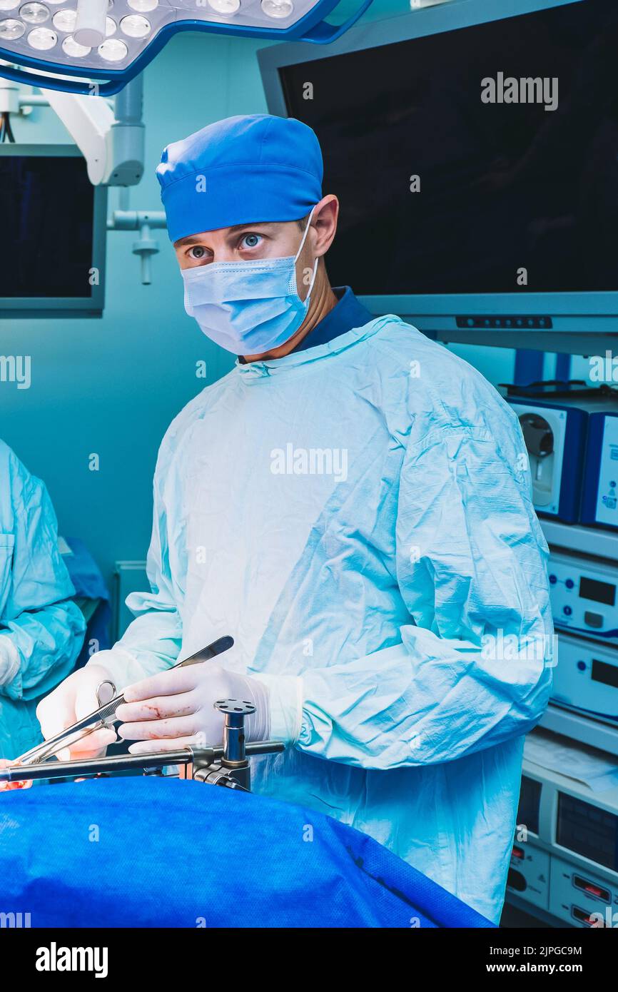 A male surgeon performs a surgical operation in the operating room. A ...