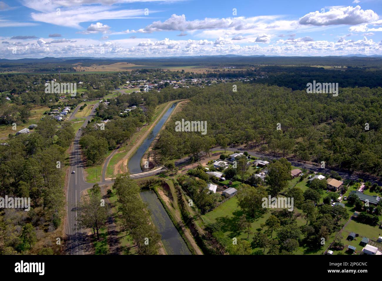 Aerial view of a curved road and irrigation canal through a suburban ...