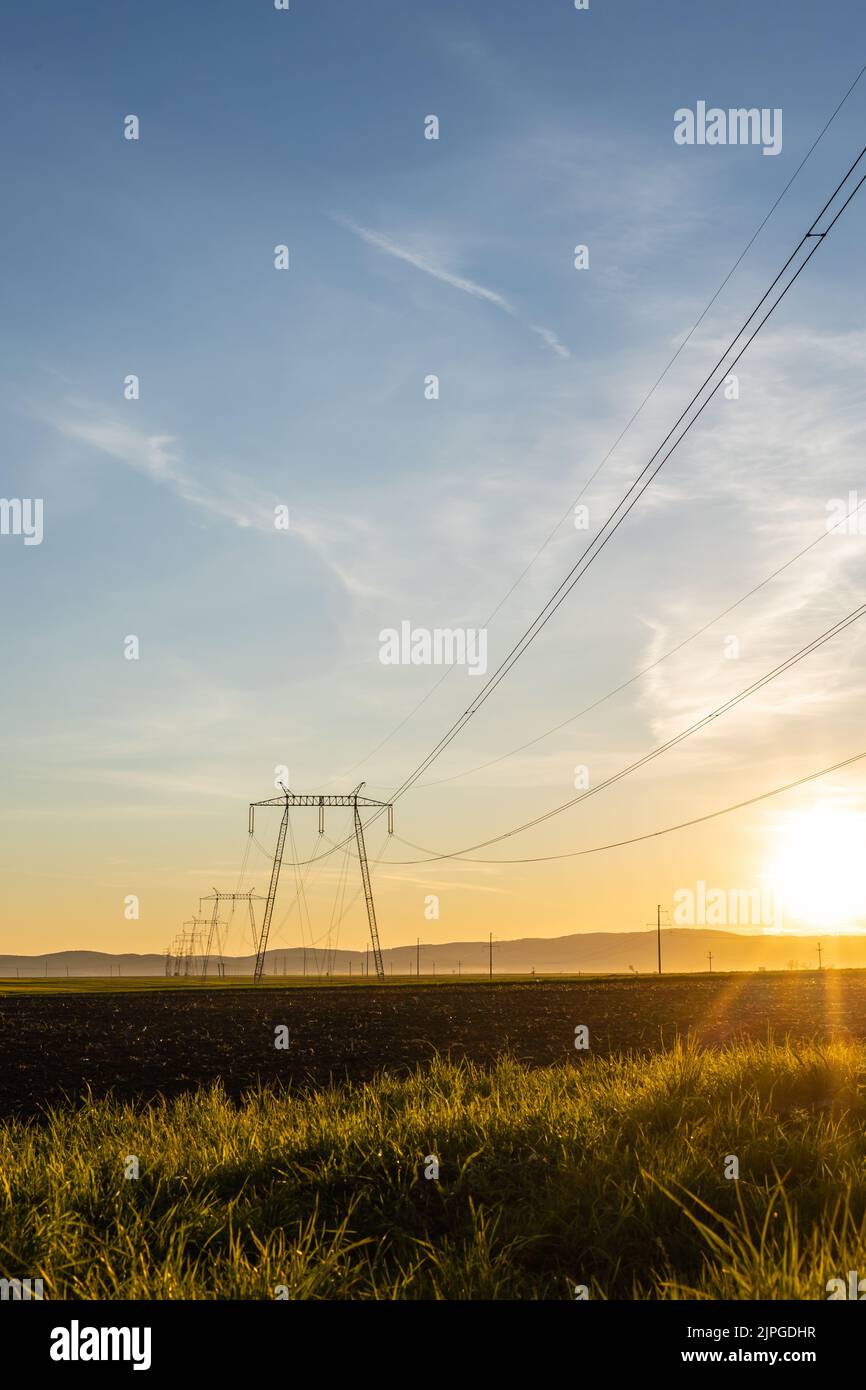 High voltage electric transmission towers and power lines at sunset ...