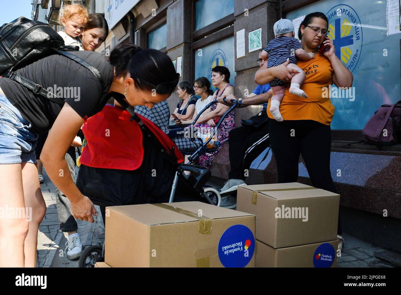 People receive boxes of food relief at a humanitarian aid distribution ...