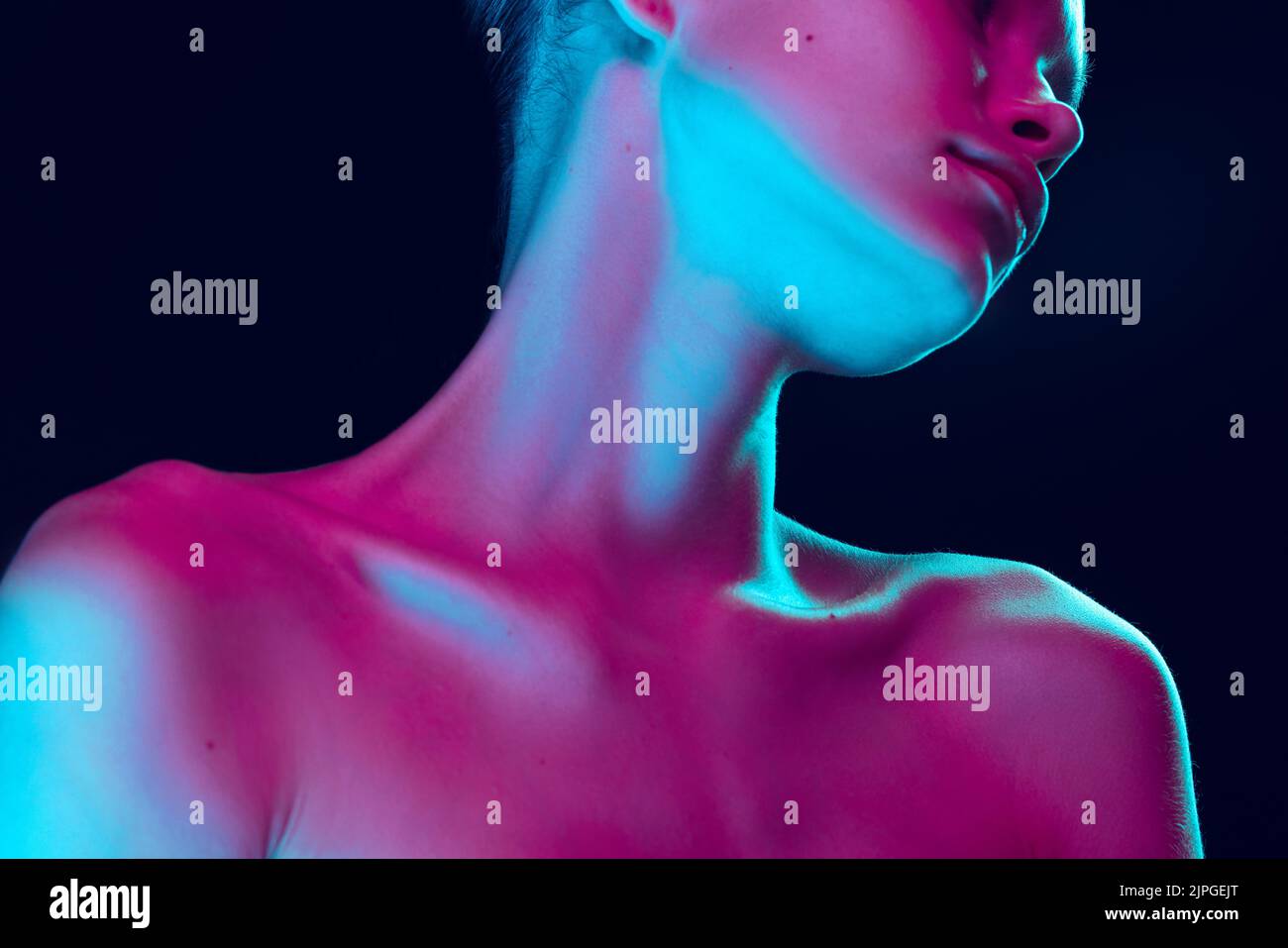 Close up female neck, collarbones and shoulders in pink neon light over ...