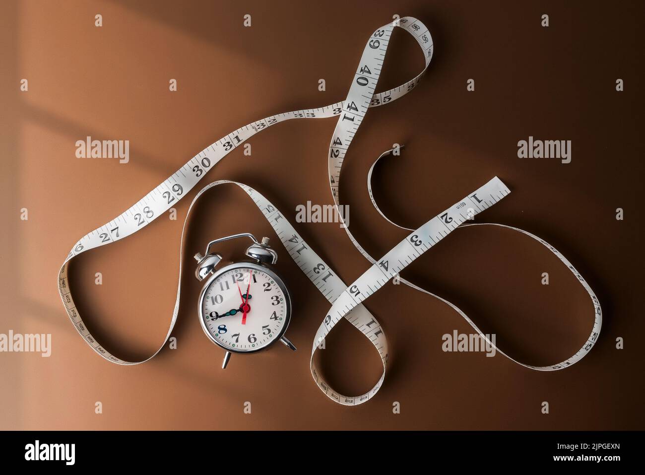 A clock surrounded by a tape measure. Time to lose weight and go on a ...