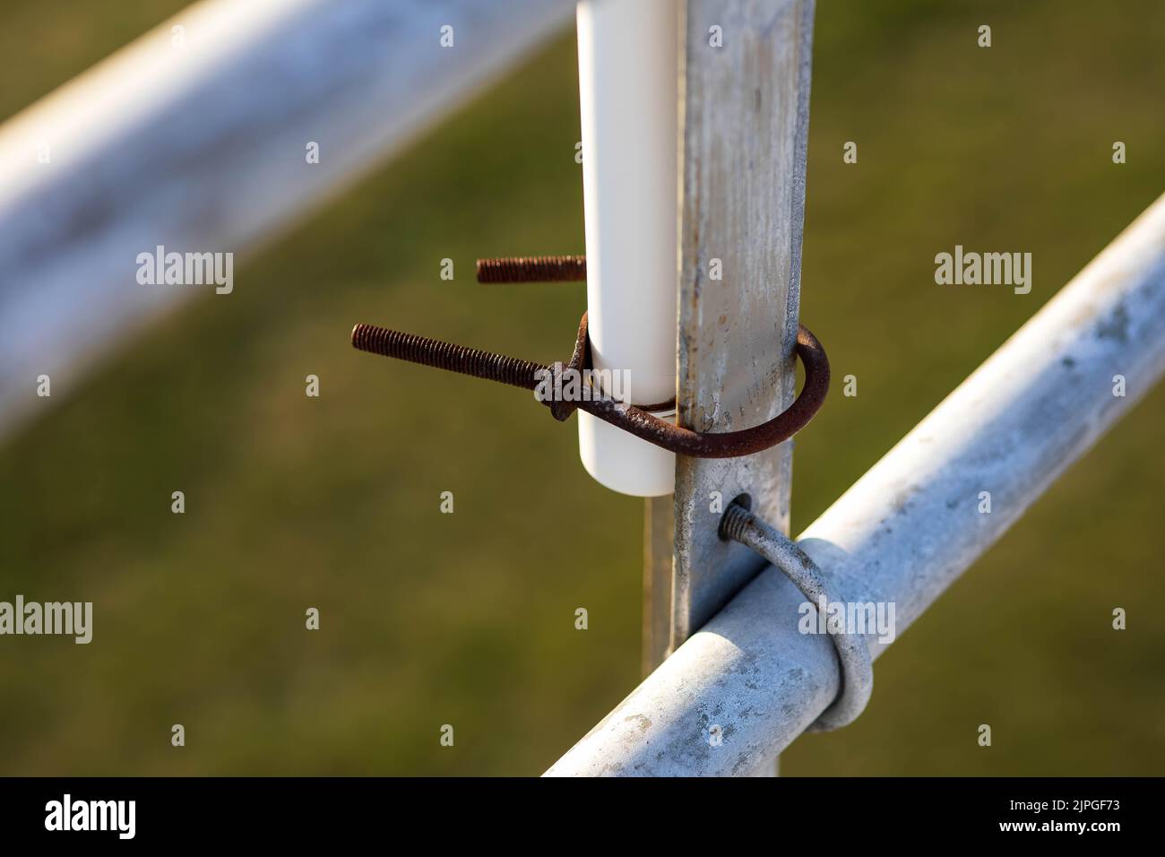 rusty clamp holding a section of plastic pipe to the back section of ...