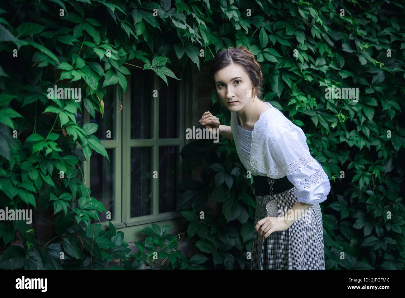 Portrait of a young slender woman in a 1910s costume. The lady peers ...