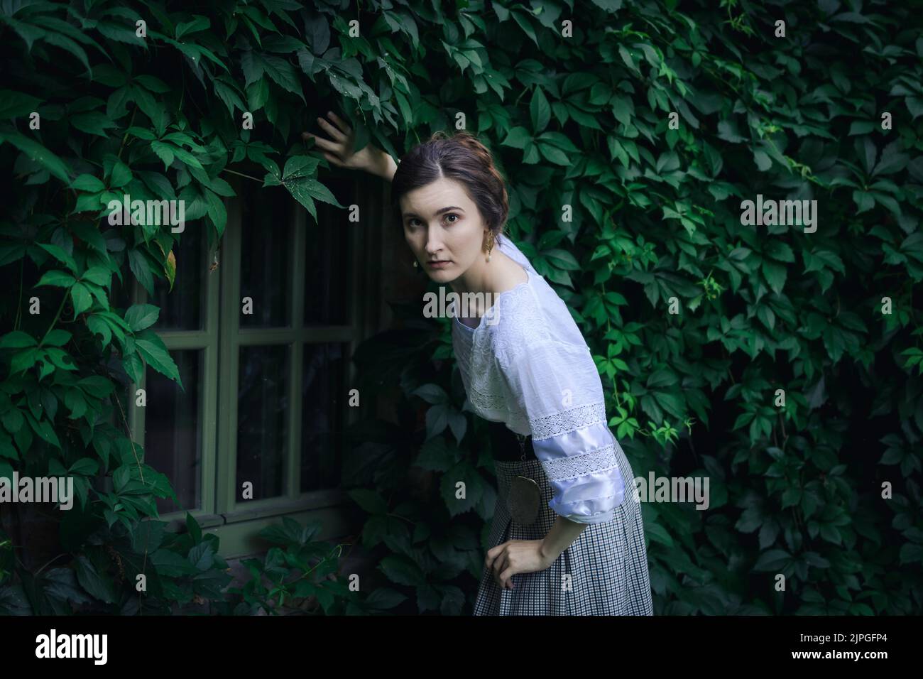 Portrait of a young slender woman in a 1910s costume. The lady peers ...