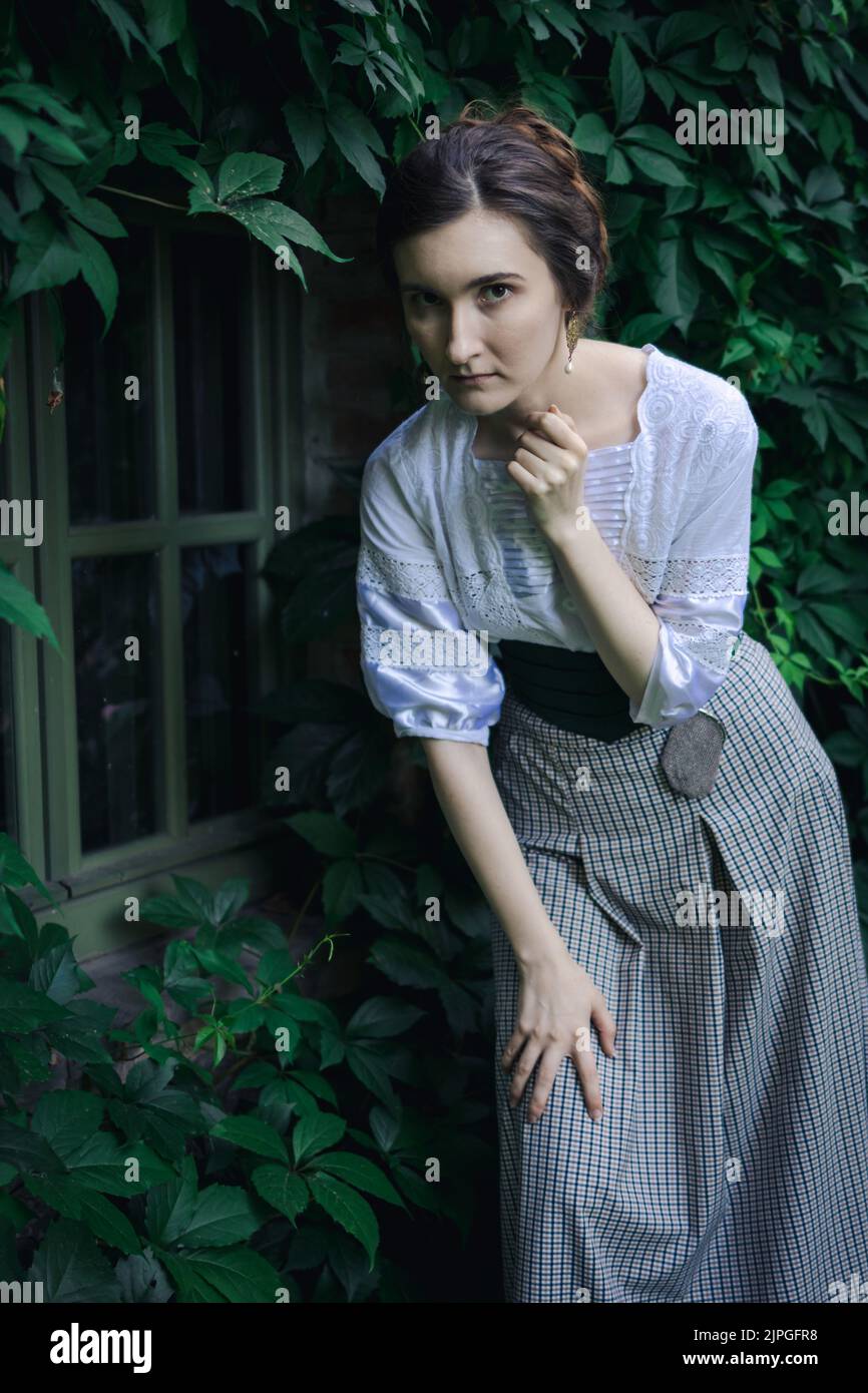 Portrait of a young slender woman in a 1910s costume. The lady peers ...