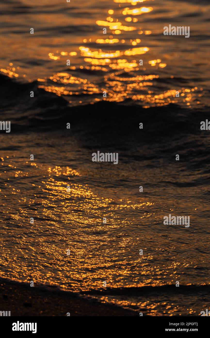 Ripple sea ocean water surface with golden sunset light. Sea wave close ...