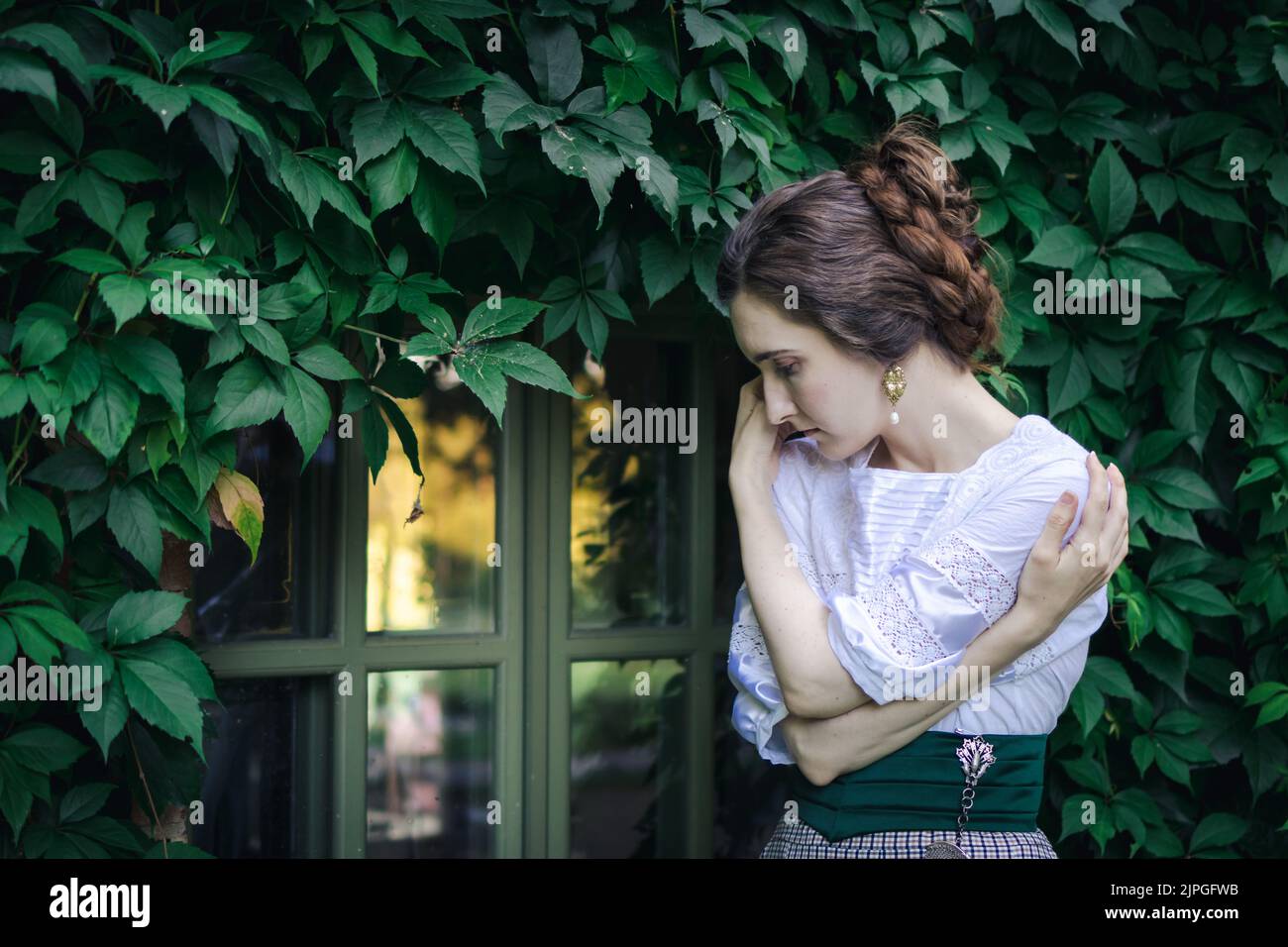 Portrait of a young slender woman in a 1910s costume. Lady near a ...