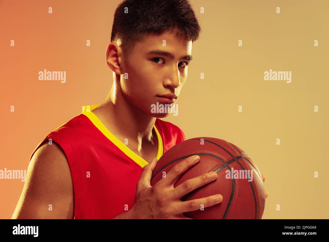 Close-up portrait of young man, basketball player posing with ball ...