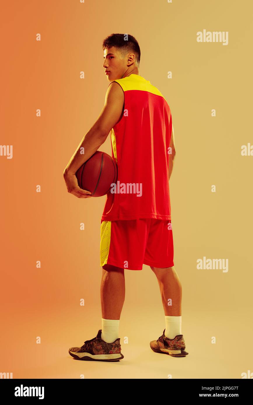 Full-length portrait of young man, basketball player posing in uniform ...