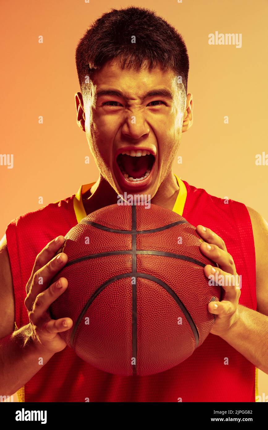 Portrait of young man, basketball player screaming, posing with ball ...