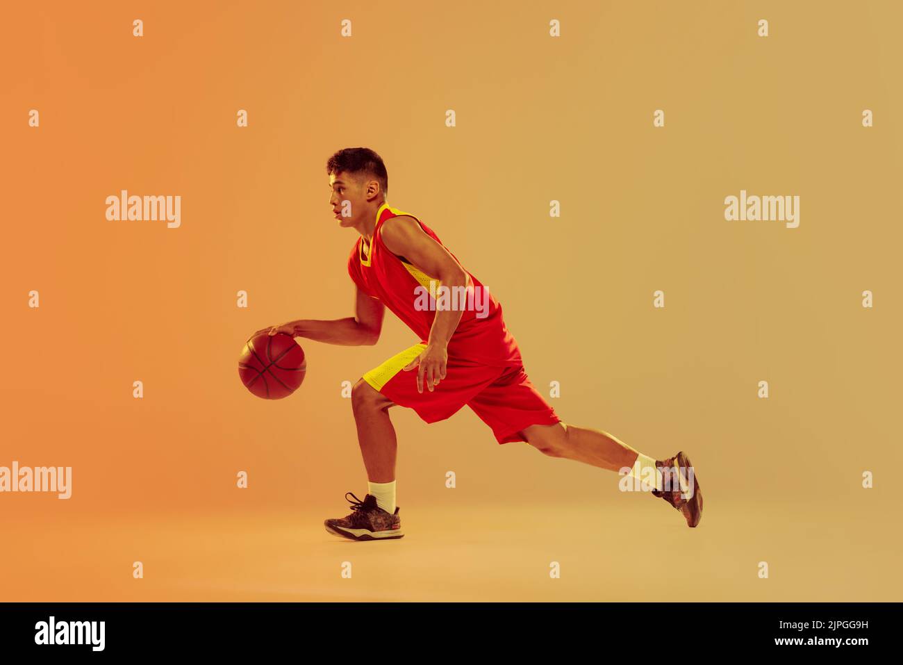 Portrait of young man, basketball player training, dribbling isolated ...