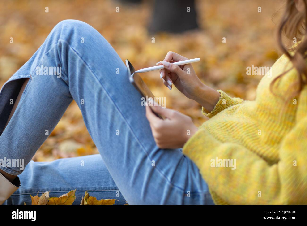 Young woman model sitting with tablet pc and painting with pencil ...