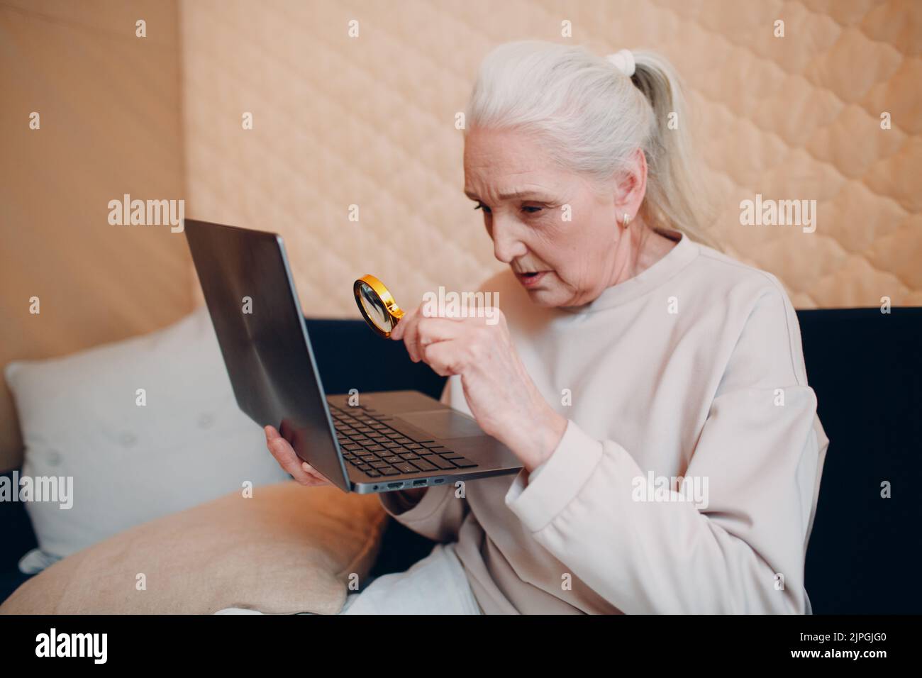 Elderly woman grandmother learns to work at home on laptop computer and ...
